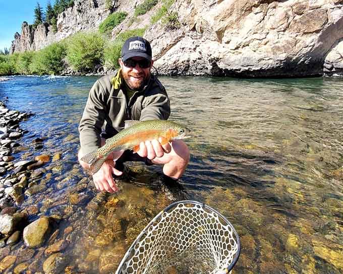 That rainbow trout's colors pop against the clear water, proving mountain streams still deliver what fishing dreams are made of.