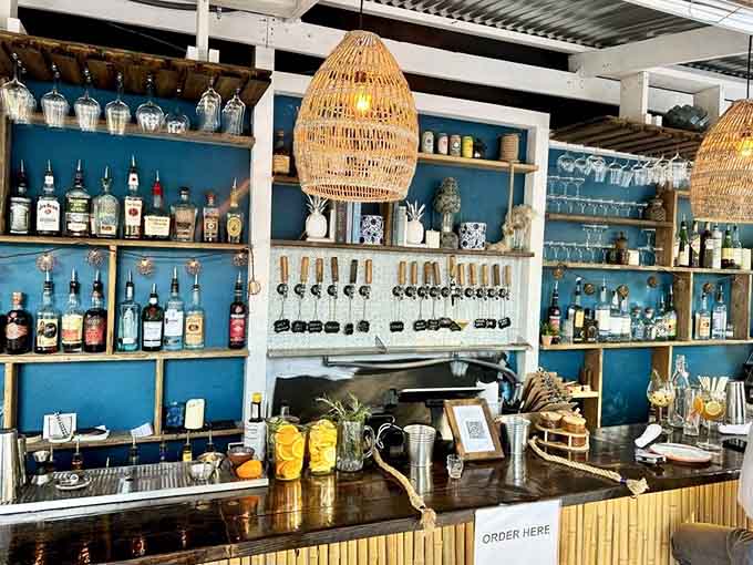 The bar area blends beachy vibes with serious beverage craftsmanship, featuring woven pendant lights and shelves of liquid possibilities.