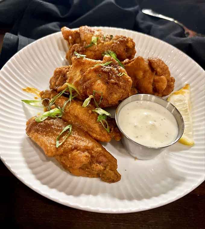 Perfectly fried chicken wings with creamy dipping sauce, the kind of appetizer that starts friendly arguments over sharing.