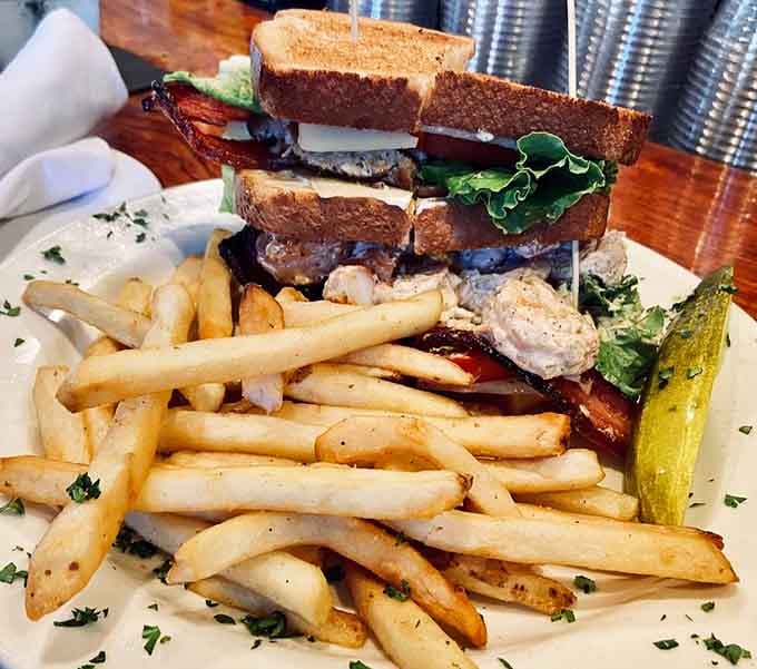 This seafood club sandwich stacked sky-high with bacon requires both hands and possibly a structural engineer to navigate.