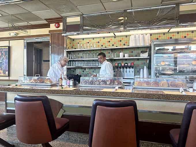 The counter where regulars sit, coffee flows eternally, and life's problems seem suddenly more manageable.