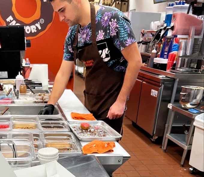 Skilled hands crafting your donuts with care, because someone has to do the important work around here.
