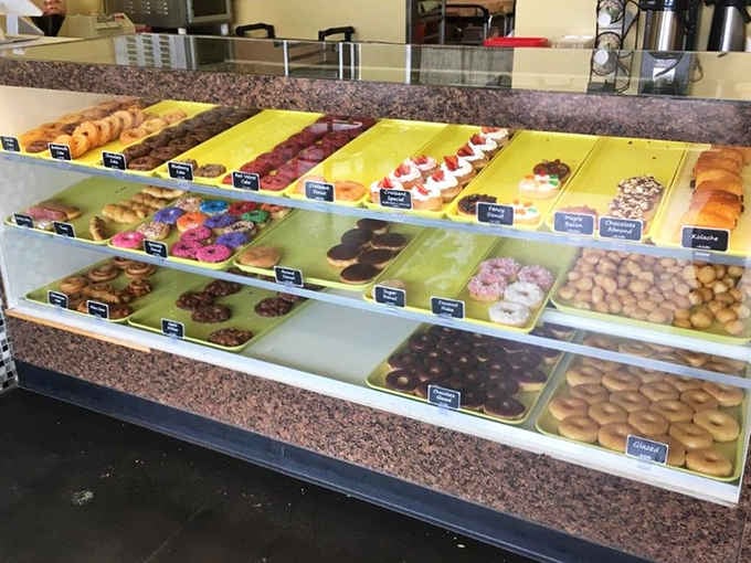 Yellow trays lined with organized rows of perfection, each donut labeled and ready for its forever home in your belly.