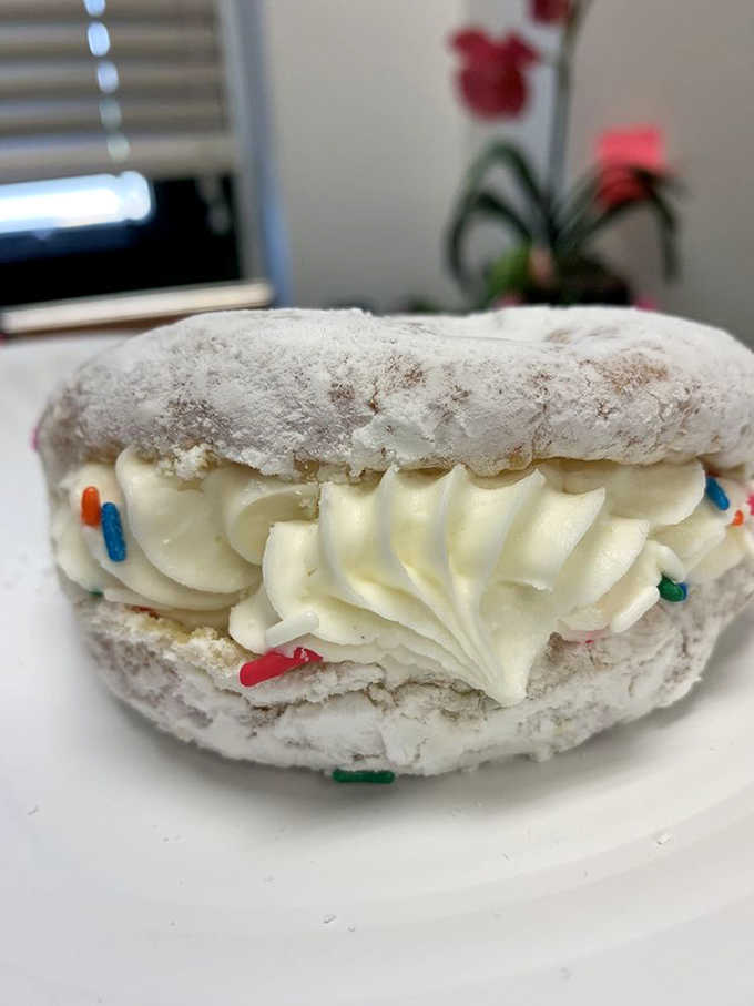 A powdered sugar cloud sandwich filled with cream, complete with festive sprinkles because every day deserves a little celebration.