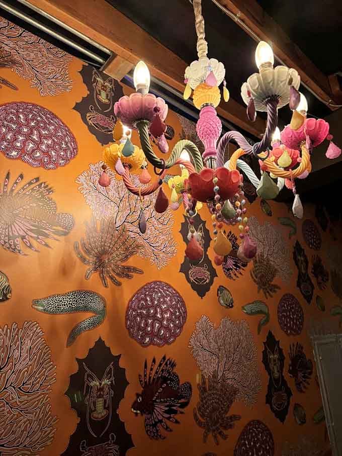 That whimsical chandelier hanging against vibrant wallpaper is basically art you can dine under while eating more art on plates.