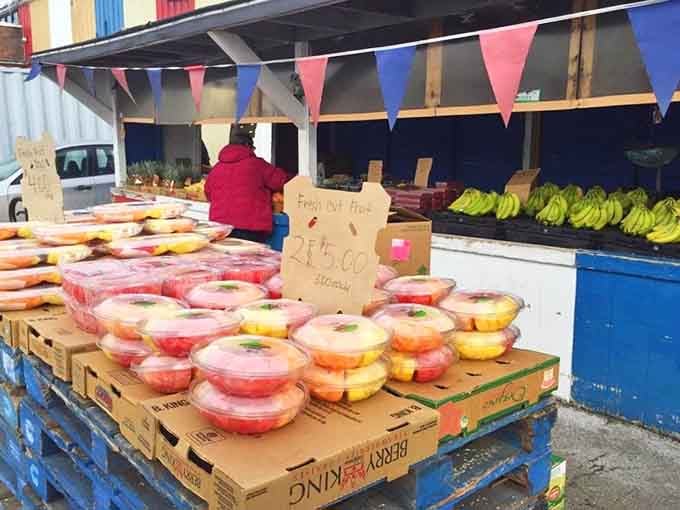 Fresh fruit displayed in containers, proving this market feeds both your shopping addiction and your actual hunger.