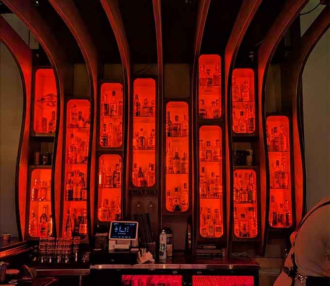 The dramatic backlit bottle display glows red like a futuristic spaceship's control panel or alien sunset.