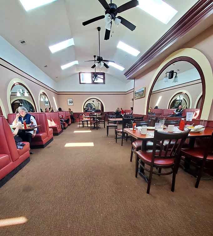 Arched openings and burgundy booths create that perfect diner atmosphere where time slows down and appetites wake up.