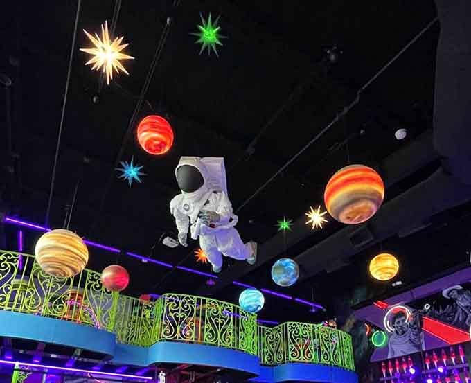 The astronaut floats overhead surrounded by planets, living its best life while you enjoy yours down below.