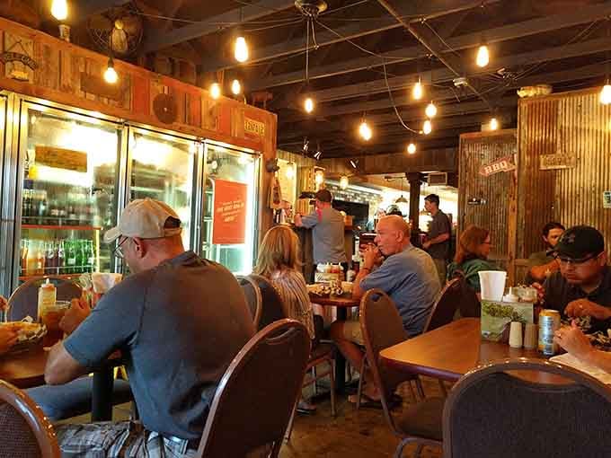 Folks gathered around wooden tables, united by the universal language of exceptional barbecue and good company eating together.
