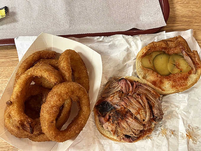 Pulled pork piled high on a soft bun with crispy onion rings, proving sandwiches can be works of art.