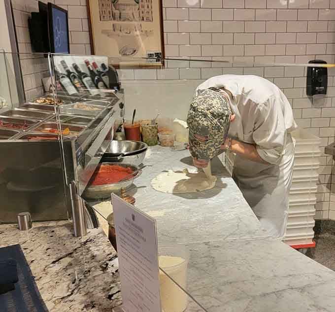 Skilled hands stretching dough by hand, honoring centuries of tradition with every careful, practiced movement.