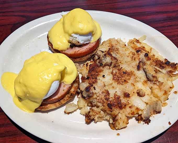 Eggs Benedict with hollandaise that flows like liquid gold over perfectly poached eggs and crispy home fries.