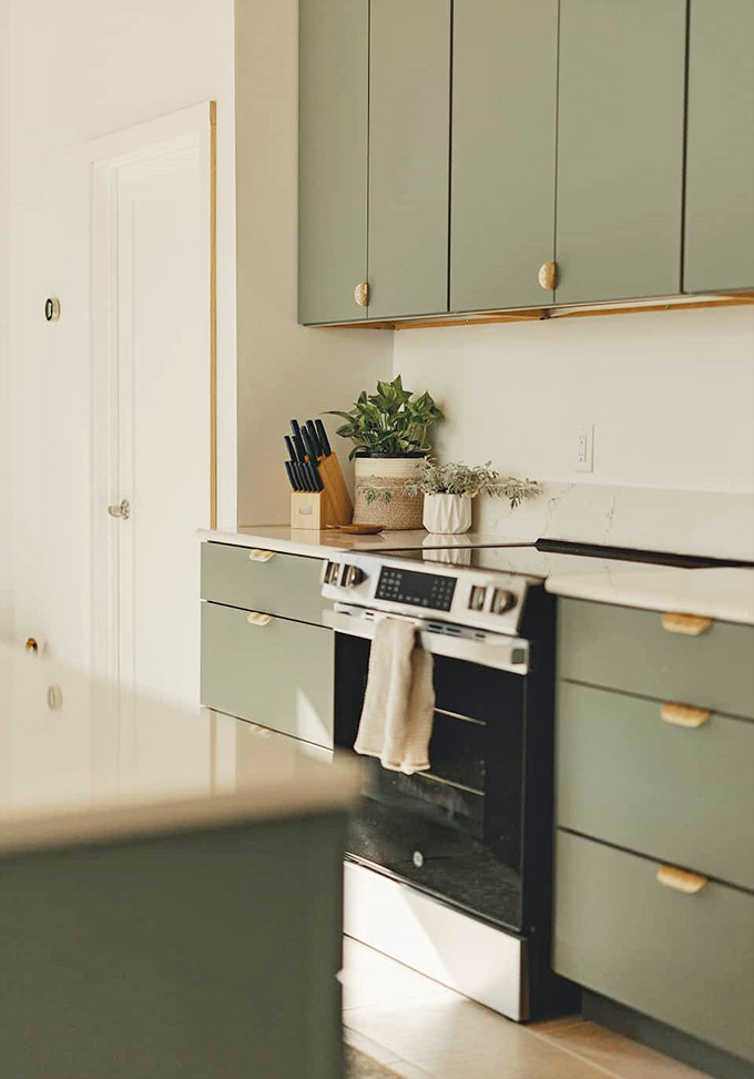 Sage cabinetry with brass hardware proves that kitchens can be both functional workspaces and legitimate works of art.