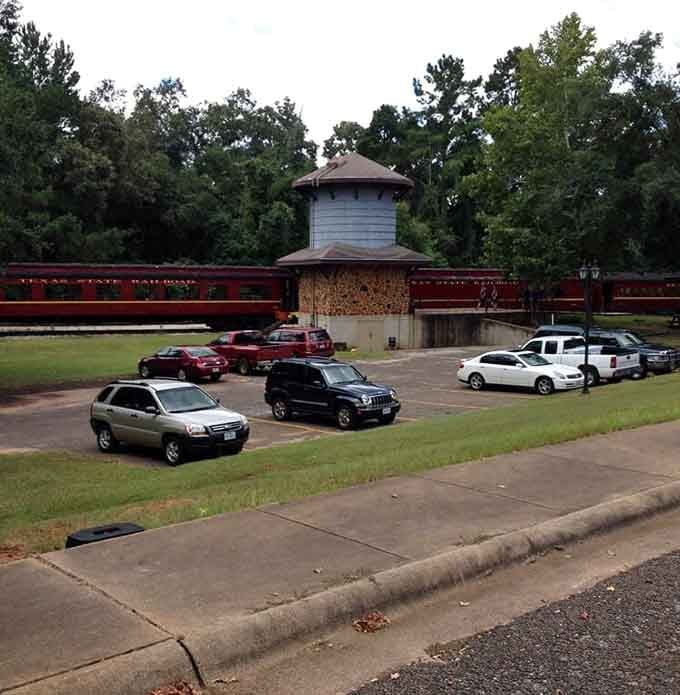 The parking area fills with modern vehicles, creating an amusing contrast against the timeless depot and vintage trains.