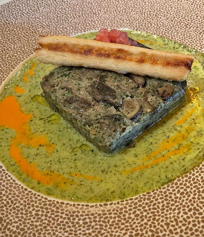 Escargot swimming in herbed butter sauce on decorative china, making snails look downright elegant and completely irresistible for once.