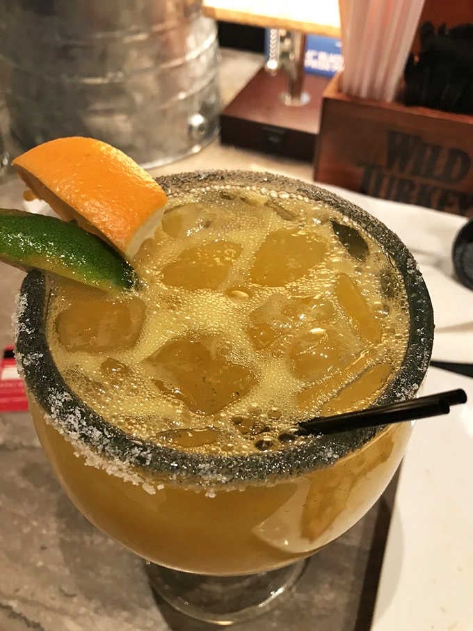 A mango margarita with a salted rim that looks like liquid sunshine in a glass, vacation mode activated.