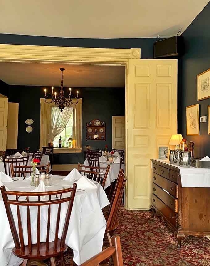 Deep teal walls and antique furnishings create intimate spaces where conversations linger over empty plates.