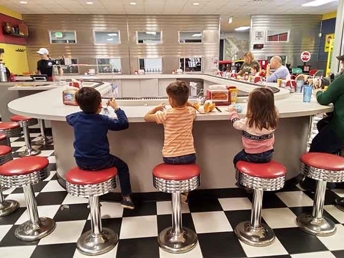 Young conductors line up at the counter, mesmerized by trains circling overhead during their meal.