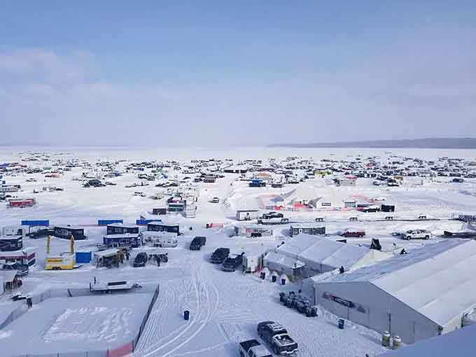 The frozen lake transforms into a temporary city where ice fishing shelters outnumber the town's actual population.