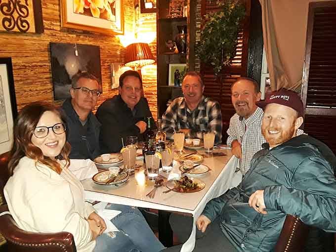 Happy diners gathered around a table, proof that good food makes everyone look like they're in a commercial.