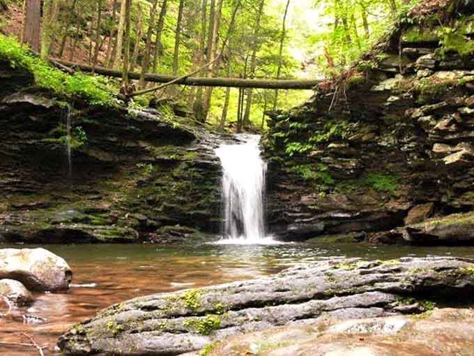A small waterfall cascades over layered rock, proving that good things really do come in compact packages.