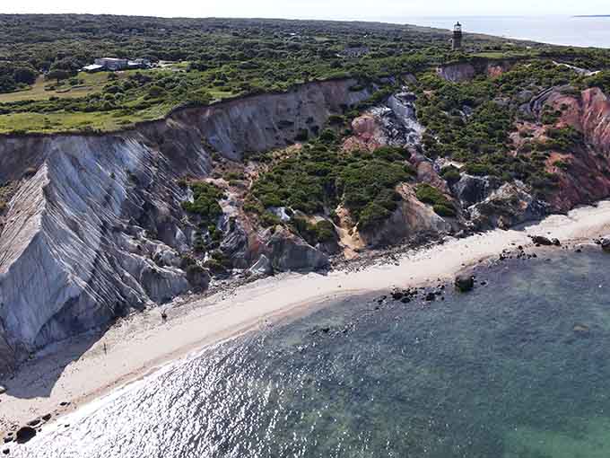 From above, the colorful cliffs embrace a crescent beach where geology becomes pure art.