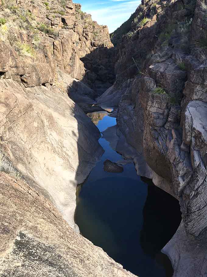 Natural rock basins hold precious water, creating mirror-like pools that reflect the surrounding canyon walls perfectly.