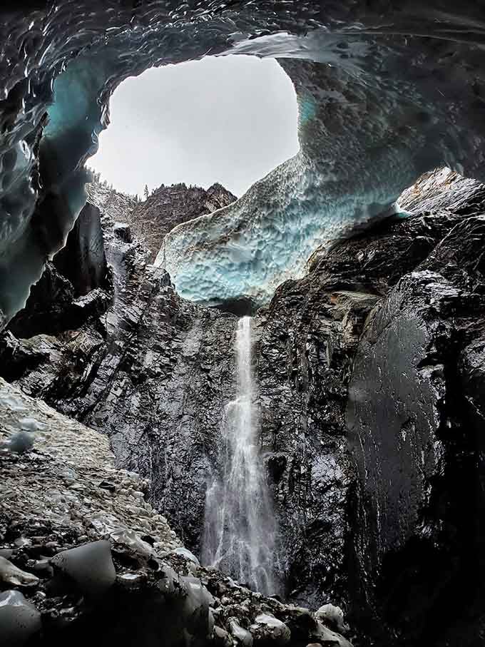 The waterfall cascading behind blue ice creates a scene straight from a fantasy novel's cover art.
