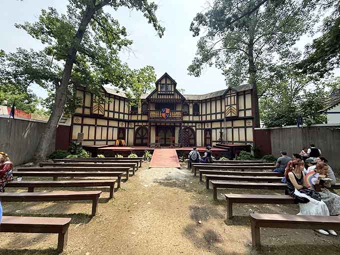 Wooden benches face the grand stage where Shakespeare and bawdy comedy share equal billing throughout long summer days.
