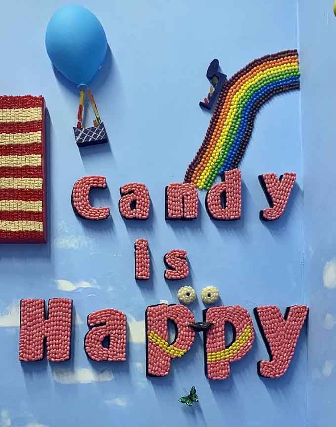 Wall art spelling "Candy is Happy" with actual candy pieces, because subtlety is overrated in paradise.