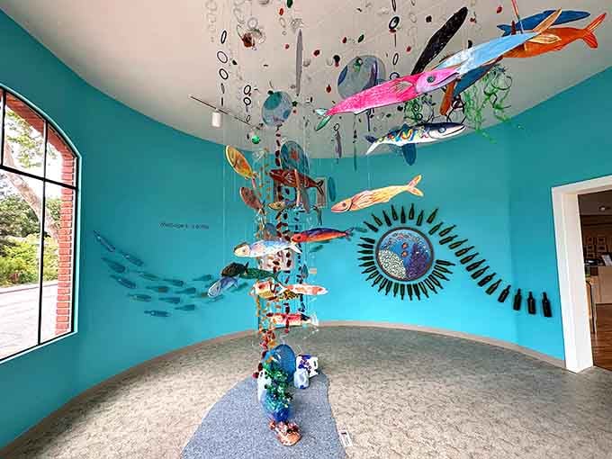 Message in a Bottle installation features colorful fish sculptures swimming through turquoise gallery waters.