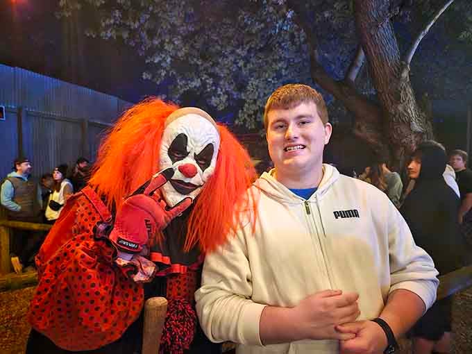 This visitor's smile suggests either genuine bravery or complete denial about what's waiting inside those haunted houses behind him.