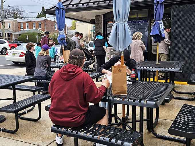 Locals gather at picnic tables, united in their appreciation for a perfectly executed cheesesteak and good company around them.