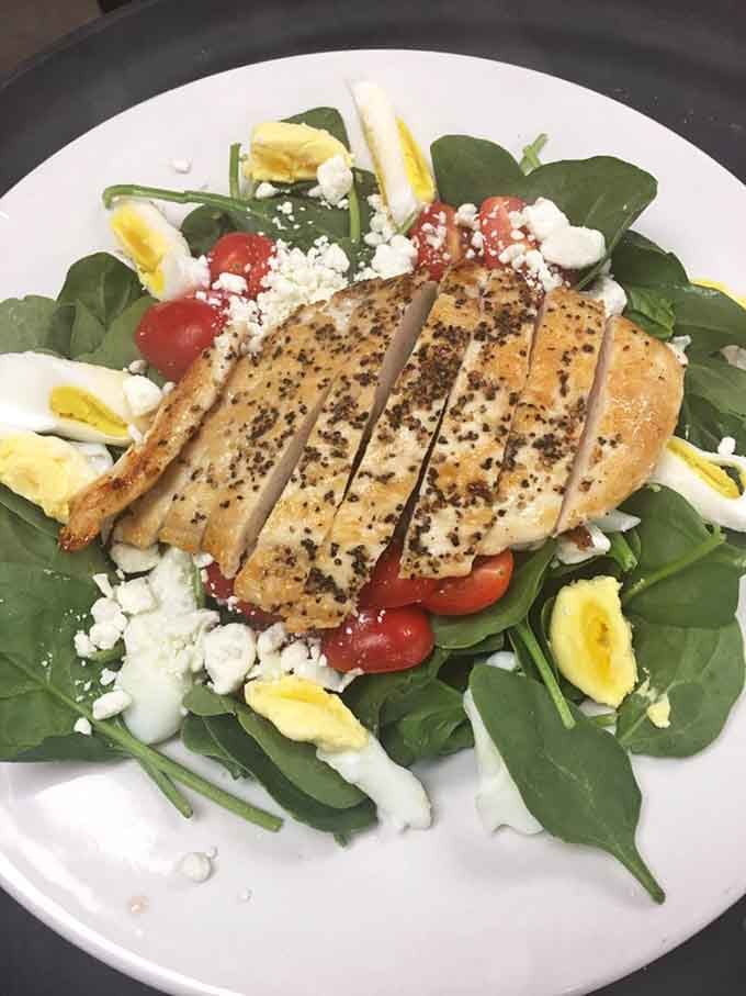 A salad topped with perfectly seasoned chicken, because even retro diners know balance is important sometimes.