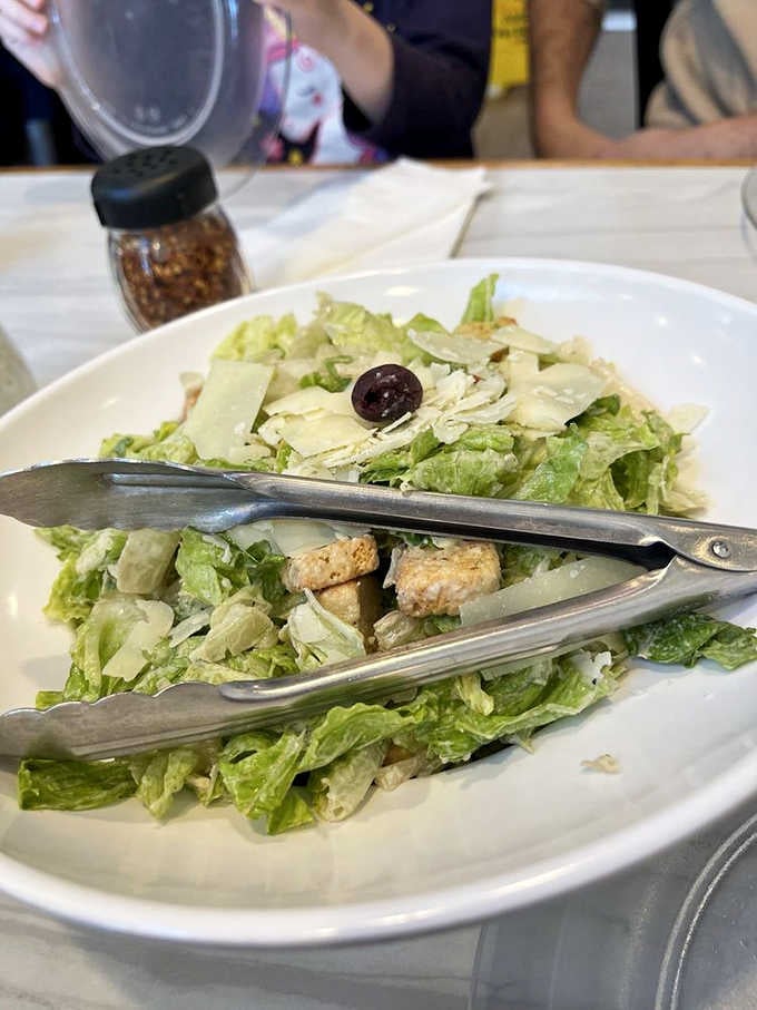 The Caesar salad provides a fresh counterpoint to all that pizza, though let's be honest about what you really came for.