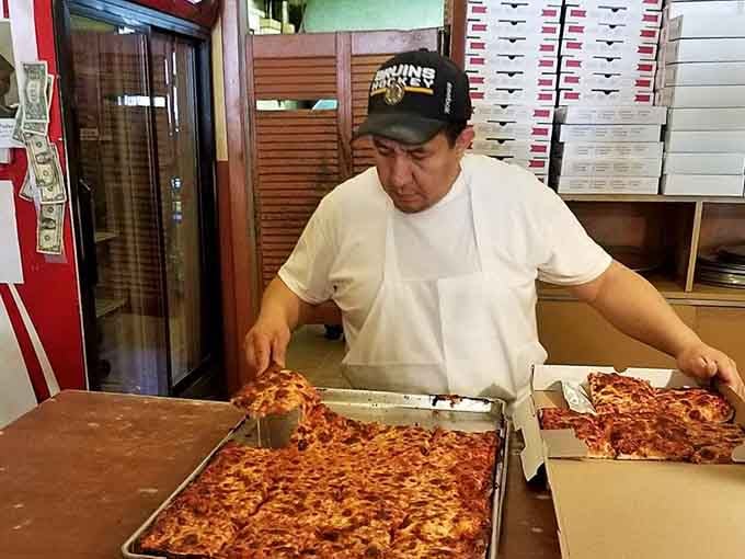 Behind the counter, skilled hands transform simple ingredients into the pizza that keeps people lining up daily.