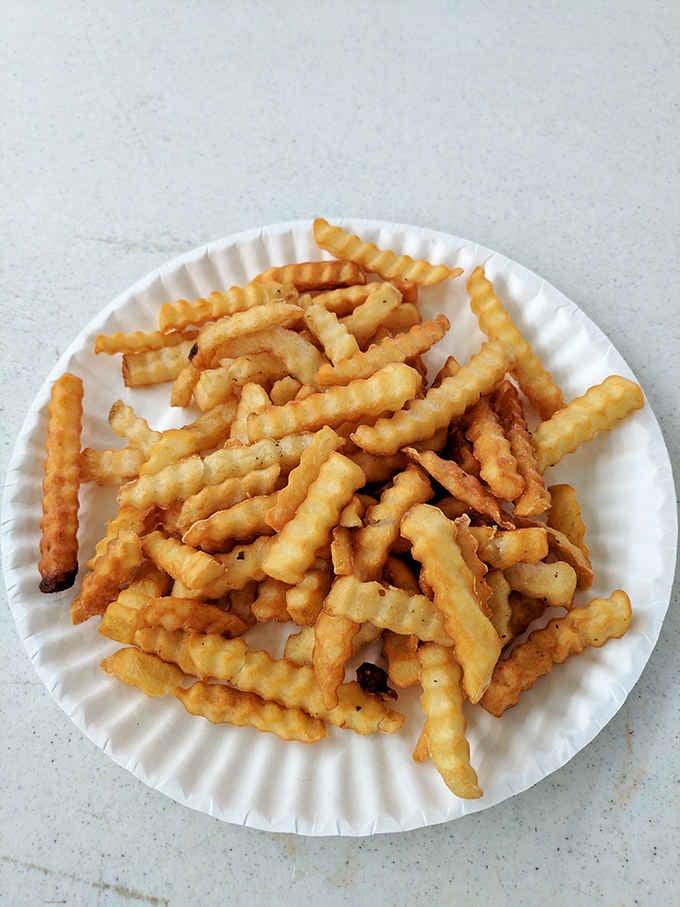 Crinkle-cut fries achieving that perfect golden color that makes you question why you ever ordered anything else.