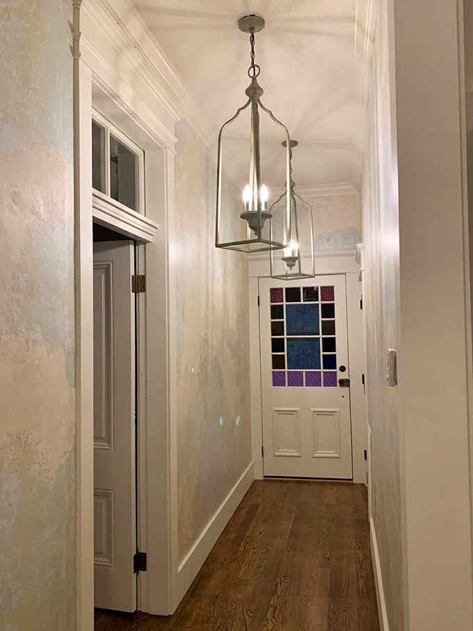 Lantern lighting and jewel-toned glass windows turn a simple hallway into something straight from a Gothic novel.