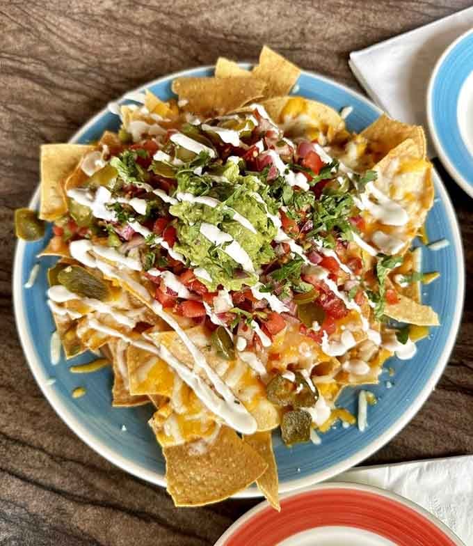 Nachos loaded with all the toppings, proving that some dishes require structural engineering degrees to eat properly.