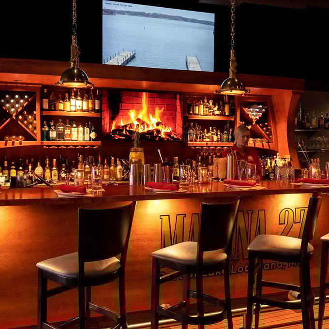 That glowing fireplace behind the bar creates ambiance that makes every drink taste better and every conversation flow easier.