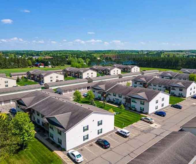 Affordable housing developments spread across green spaces, proving the American Dream didn't die but simply relocated to sensible places.