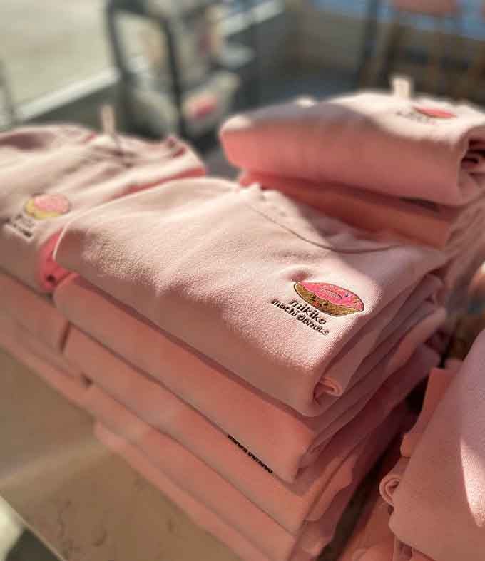 Branded merchandise in soft pink proves that donut loyalty runs deep enough to warrant taking home a souvenir sweatshirt.