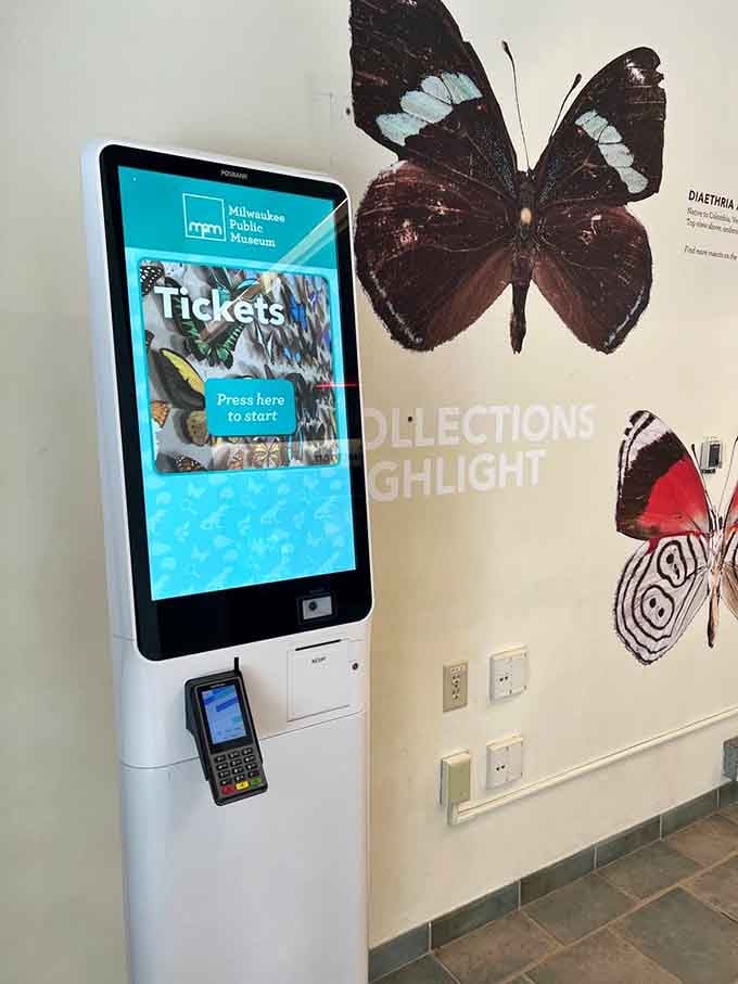 Modern ticket kiosks make entry easy, though the real butterflies on the wall steal the show from technology.