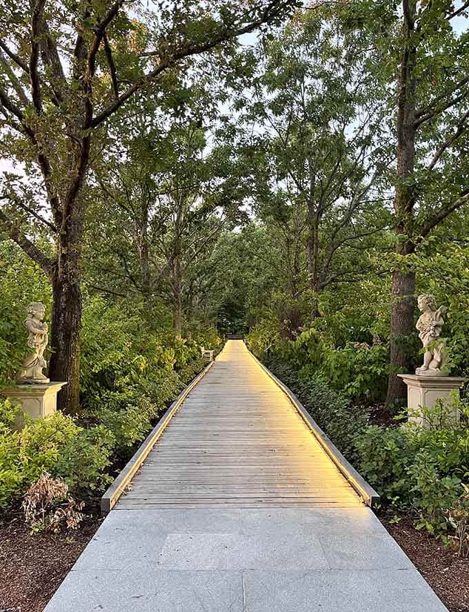 This tree-lined pathway flanked by classical statues feels like walking through a living museum of natural elegance.