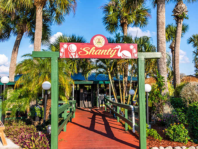 The Shanty Lounge beckons with its cheerful red sign, promising cold drinks and good times by the water.