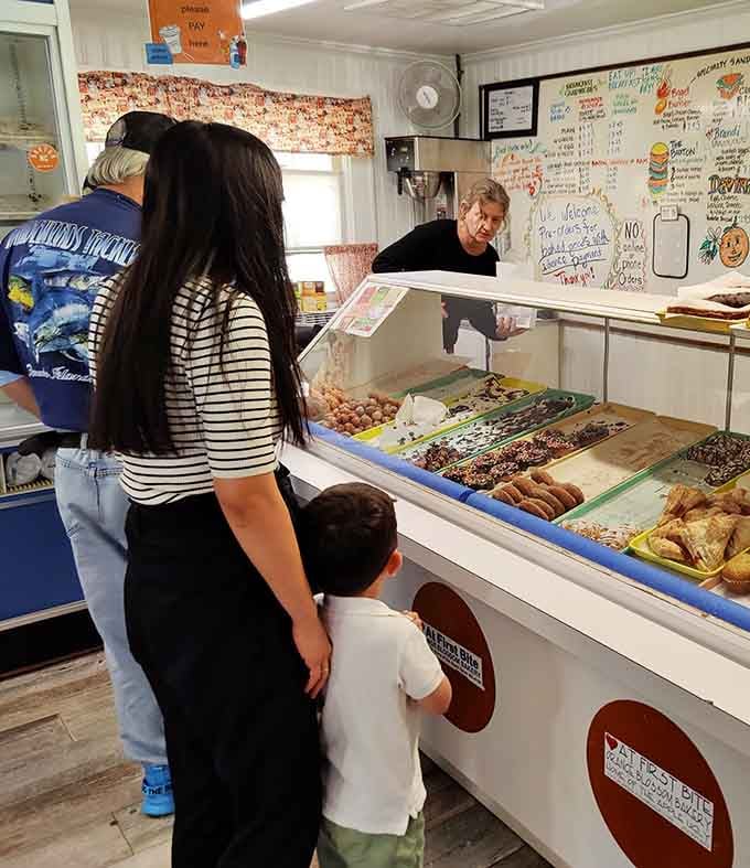 The pastry case gleaming with fresh-baked treasures while eager customers make the hardest decisions of their morning.