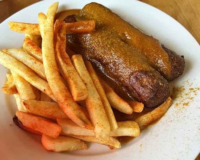 Currywurst glistening with that addictive curry ketchup sauce, proving street food can be just as crave-worthy on a proper plate.