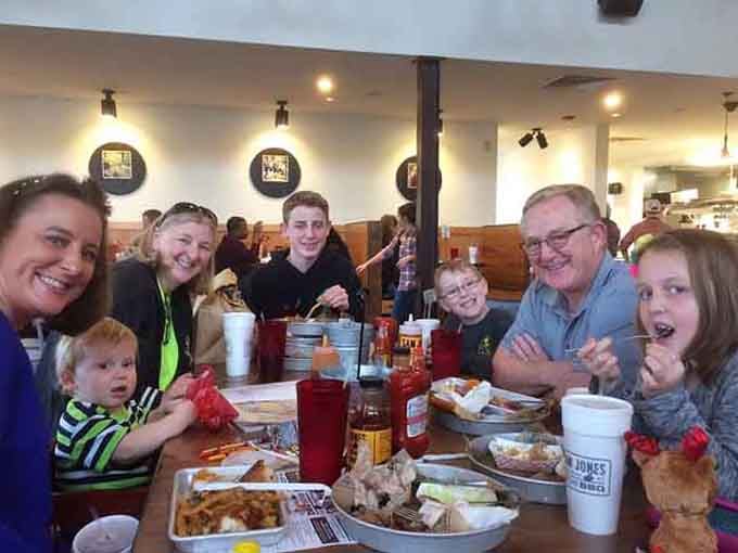 Multiple generations gathered around tables piled with barbecue—this is what family meals are supposed to look like.