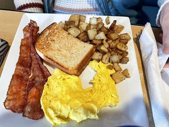 Classic breakfast plate with crispy bacon, fluffy eggs, and golden hash browns fueling your beach day properly.